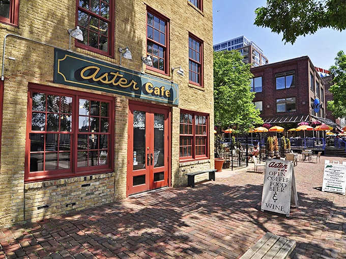 The golden-hued brick facade of Aster Cafe stands as a welcoming beacon on St. Anthony Main, its vintage sign promising good times within.