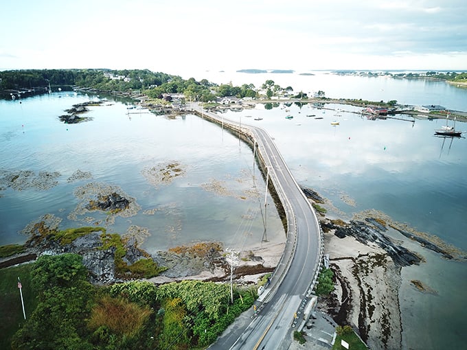 Aerial view of the Bailey Island Bridge stretching across the water, connecting islands with its distinctive cribstone pattern.