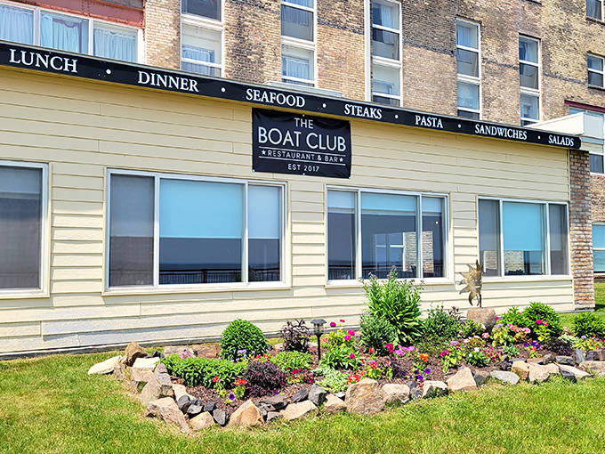The Boat Club's welcoming exterior promises maritime delights, with colorful flower beds softening the historic brick façade.