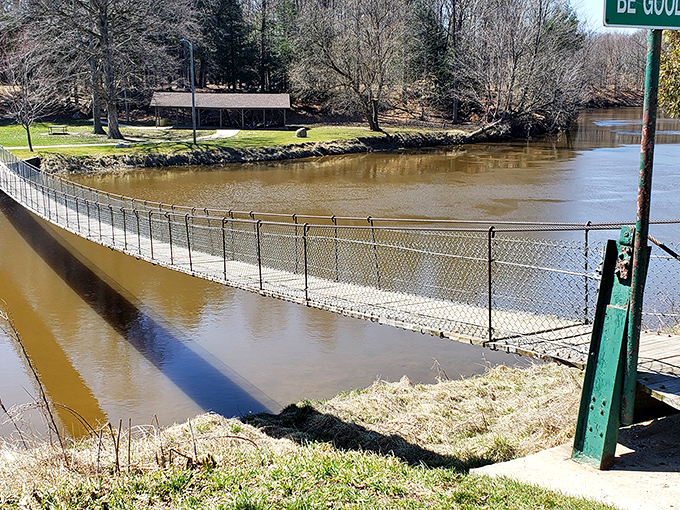 The Croswell Swinging Bridge stretches across the Black River like a wooden ribbon, inviting brave souls to test their balance and nerve.