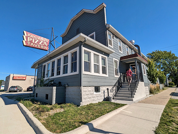 Exterior: The blue house with the iconic red "Fricano's Pizza Tavern" sign stands unassumingly on the corner, hiding Michigan's pizza treasure within its humble walls.