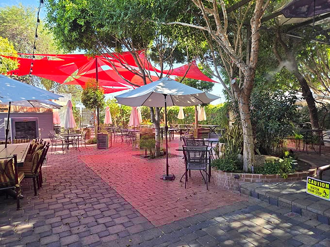 The Perch's inviting outdoor patio beckons with brick pavers and vibrant red umbrellas, creating an oasis of shade in the Arizona heat.