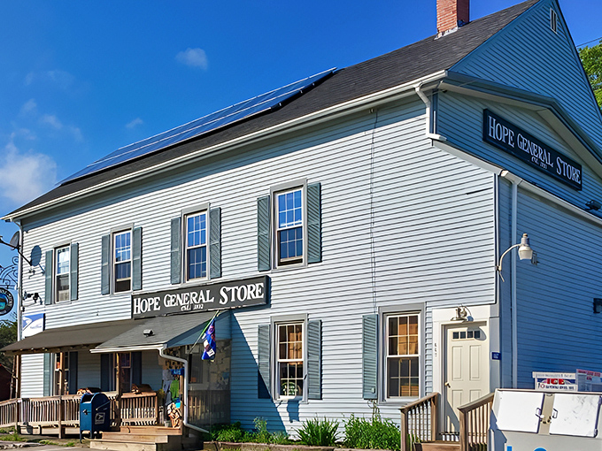 The iconic pale blue clapboard exterior of Hope General Store stands proudly against the Maine sky, solar panels blending history with forward-thinking practicality.