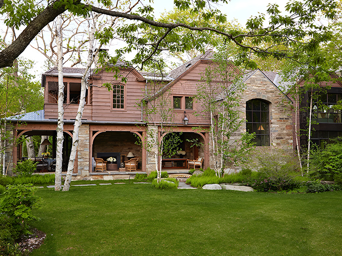 A harmonious blend of Maine craftsmanship and African elegance, this exterior view showcases natural stone and warm wood tones.