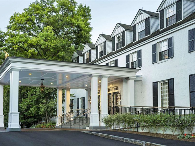 The grand entrance of Woodstock Inn welcomes visitors with stately columns and perfect symmetry &ndash; architectural elegance that whispers "you've arrived somewhere special."