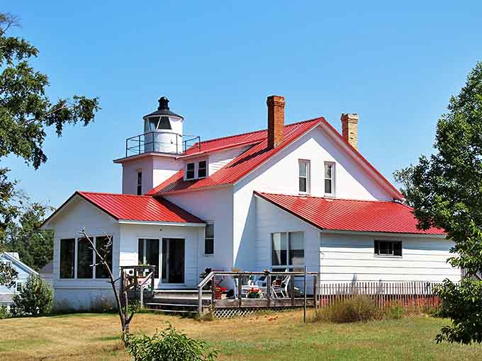 The historic Eagle River Lighthouse stands proudly with its distinctive white walls and bright red roof, a maritime sentinel now welcoming travelers instead of ships.