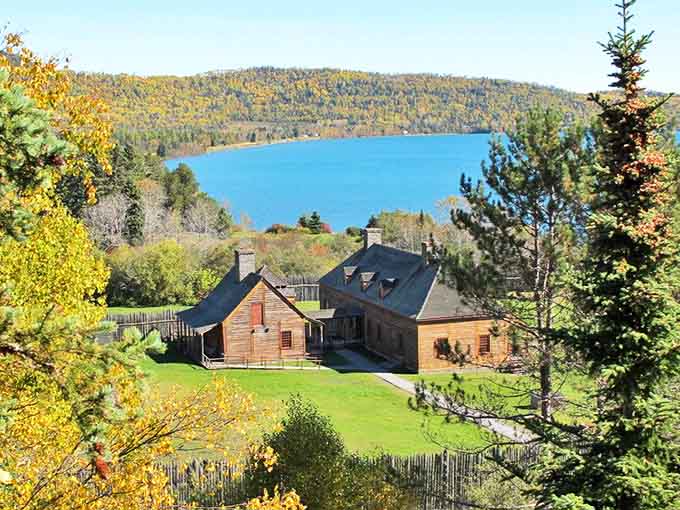 Historic Grand Portage nestled between vibrant autumn foliage and the shimmering blue expanse of Lake Superior&mdash;nature's perfect frame for centuries of stories.