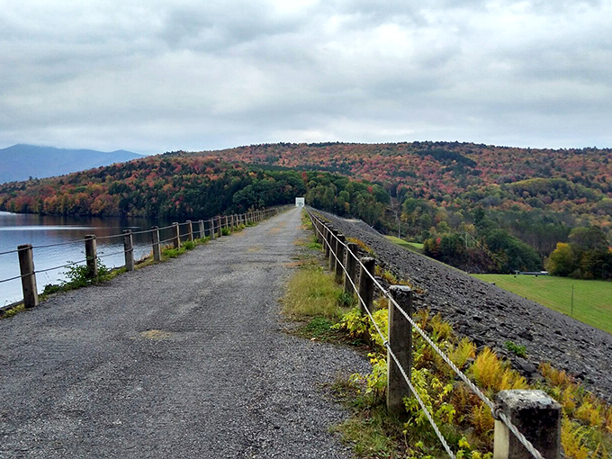 The historic dam path stretches across Waterbury Reservoir, offering panoramic views of Vermont's autumn splendor that'll make your heart skip several beats.