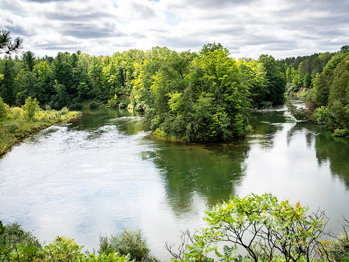 The Manistee River curves gracefully through Michigan's forests like nature's own watercolor painting, reflecting sky and trees in its glassy surface.