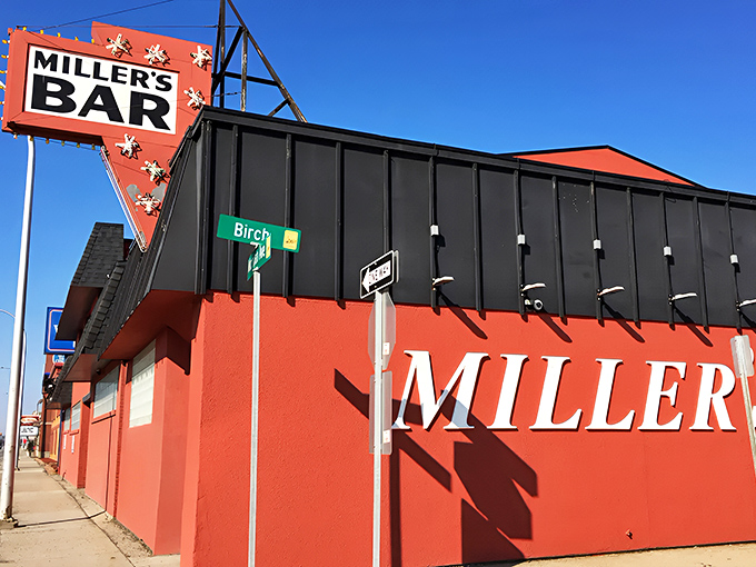 The iconic red exterior of Miller's Bar stands proudly at the corner of Michigan Avenue and Birch Street, its vintage sign a beacon for burger lovers since the 1940s.