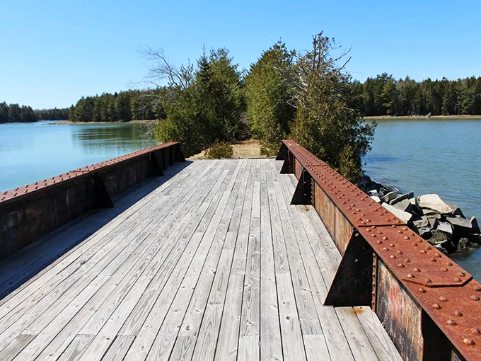 Where water meets history: The Old Pond Railway Trail's wooden deck extends into the tranquil waters, inviting visitors to pause and reflect.