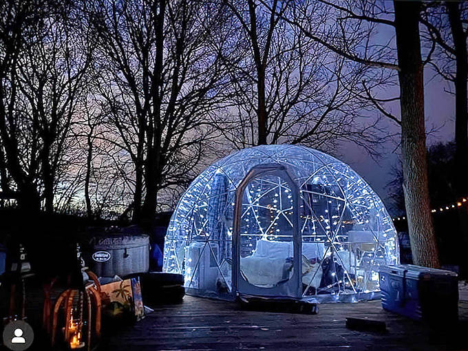 A glowing geodesic dome creates a magical snow globe effect against the twilight sky, promising an enchanted overnight experience.