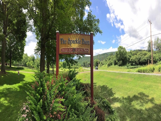 The Sparkle Barn sign stands proudly against Vermont's lush landscape, promising treasures that somehow exceed even the wildest expectations.