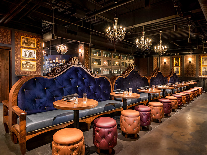 Elegance meets mystery in this plush seating area where navy tufted booths invite intimate conversations under the glow of crystal chandeliers.