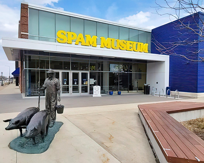The SPAM Museum's striking exterior welcomes visitors with bold yellow signage and a bronze farmer statue, standing proudly against Minnesota's blue skies.