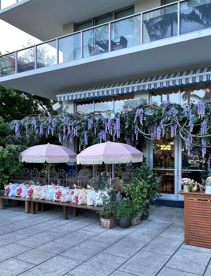Wisteria dreams come true at Little Hen's enchanting entrance, where pink umbrellas and cascading purple blooms transform Miami concrete into a fairytale setting.