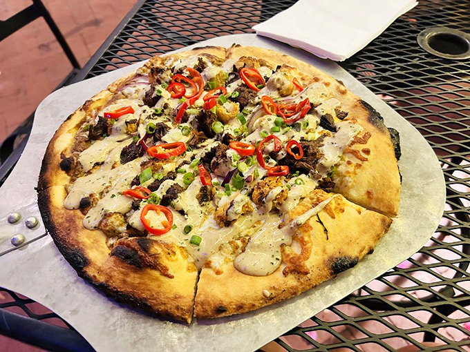 A pizza masterpiece emerges from The Perch's kitchen, topped with colorful peppers and savory morsels on a perfectly charred crust.