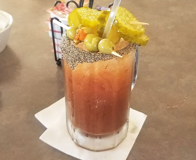 The Bloody Mary arrives as a vegetable garden in a glass, garnished so elaborately it qualifies as both beverage and appetizer simultaneously.