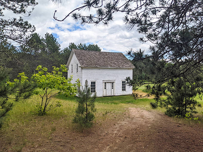 The Beaulieu House stands in solitary splendor, its weathered white clapboard a canvas for shadows cast by surrounding pines.