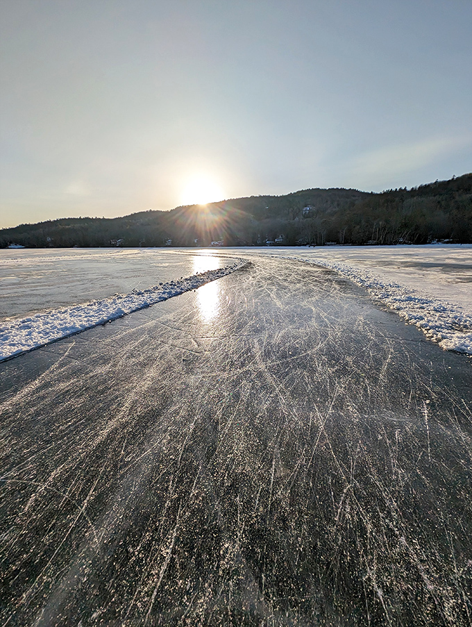 Winter's crystalline artistry transforms the lake into nature's skating rink, with sunlight dancing across ice that holds countless memories of winters past.