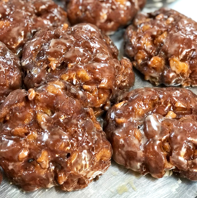Apple fritters glistening with glaze that captures light like stained glass windows in the Cathedral of Carbs. Worth every sticky finger.