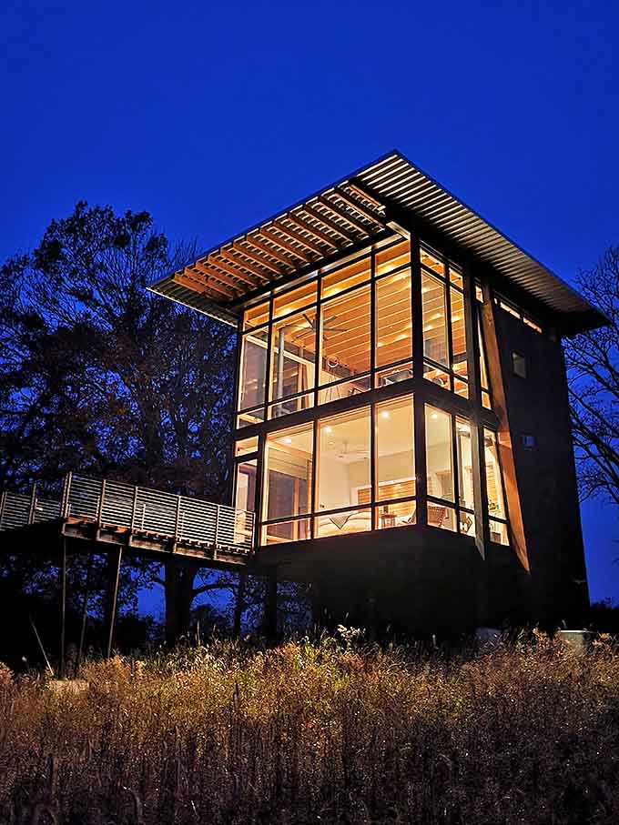 Stars puncture the darkness above while the bridge stands sentinel below, its wooden frame silhouetted against the cosmic light show.