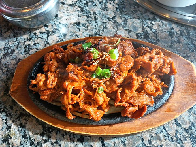 Spicy pork sizzles on the tabletop grill, caramelizing to perfection as the marinade creates a sweet-spicy glaze that will haunt your dreams.