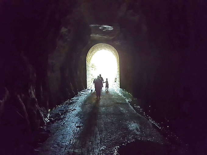From darkness to light &ndash; emerging travelers become silhouettes against the tunnel's bright exit, a metaphor in motion.