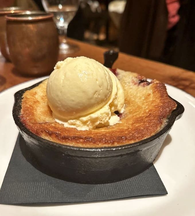 Strawberry cobbler in a cast iron skillet topped with ice cream, because some desserts are worth loosening your belt for.