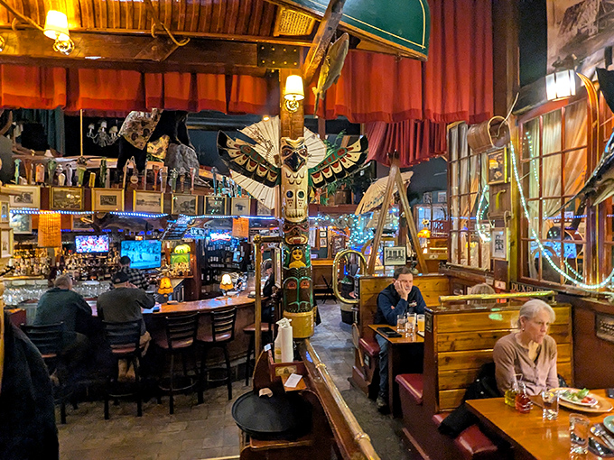 The dining room buzzes with conversation as patrons enjoy their meals beneath wooden beams and surrounded by decades of collected curiosities.