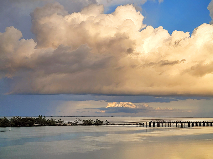Reflections dance on calm waters surrounding this pristine pier, where fishing dreams and sunset memories are made daily.