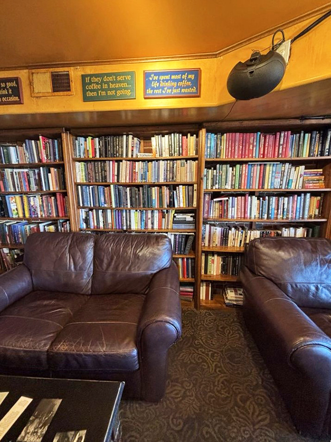 Leather couches nestled between towering bookshelves create the ultimate reading nook, with coffee-themed wisdom displayed overhead for contemplation.