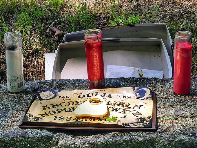 Paranormal investigators often find ritual items like these candles and Ouija boards left behind – cemetery caretakers discourage such practices.