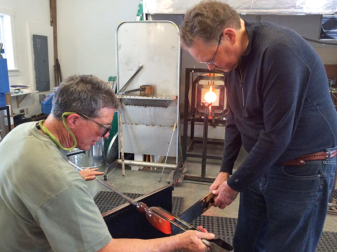 Two craftsmen work in synchronized harmony, demonstrating why glassblowing has always been a collaborative art form.