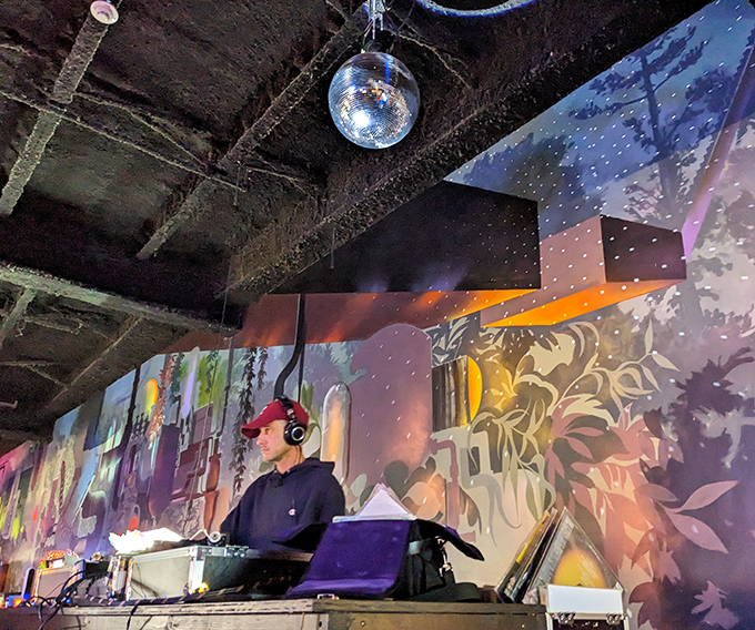 The DJ booth transforms into command central at night, mixing beats that somehow perfectly complement both 80s arcade games and contemporary cocktails.