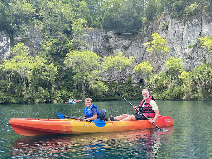 Kayakers glide across mirror-like waters, dwarfed by the impressive limestone cliffs that create this unexpected Florida landscape.