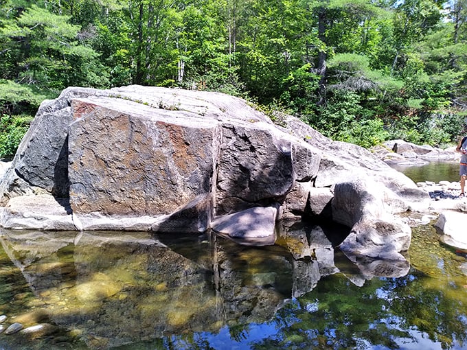 Clear water and smooth granite rocks create a peaceful summer escape at Coos Canyon, a favorite spot for relaxing in Byron, Maine.