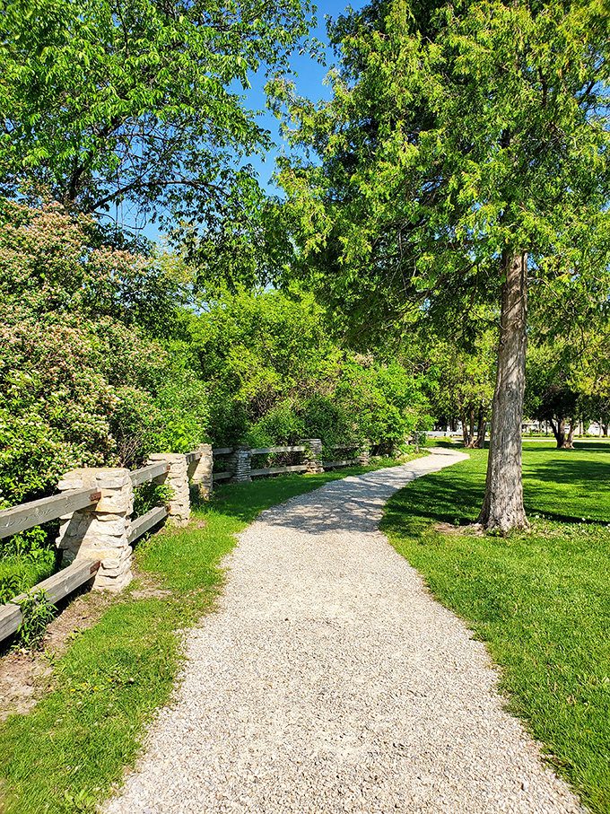 Sunlight dapples this inviting gravel path, where limestone walls whisper geological secrets to those who pause to listen.