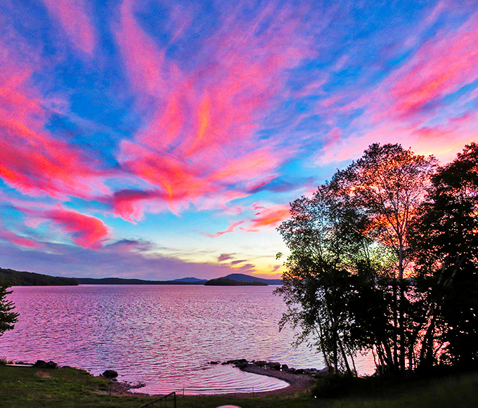 Nature's light show outperforms any Broadway production as sunset paints the sky in impossible colors, reflecting perfectly on Rangeley's mirror-like surface.