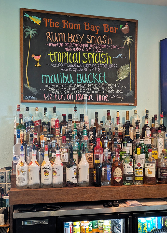 The well-stocked bar showcases an impressive collection of rums and spirits, with a chalkboard highlighting signature tropical concoctions.