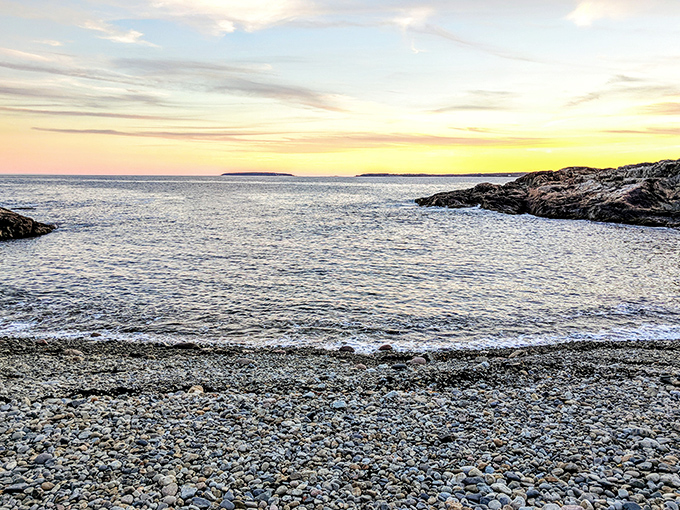 The pebble beach curves gently between rocky outcroppings, a hidden smile on Maine's rugged coastal face.