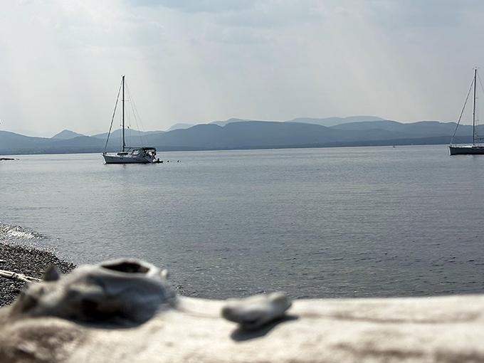 Sailboats drift lazily across Lake Champlain's waters, adding postcard-perfect elements to an already stunning view.