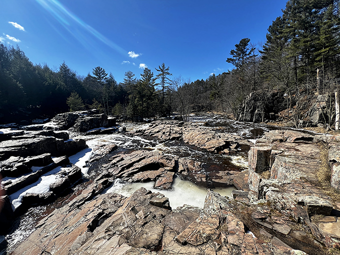 Winter's icy grip transforms the rocky riverbed into a crystalline landscape, where summer's rushing waters pause in their geological sculpting work.