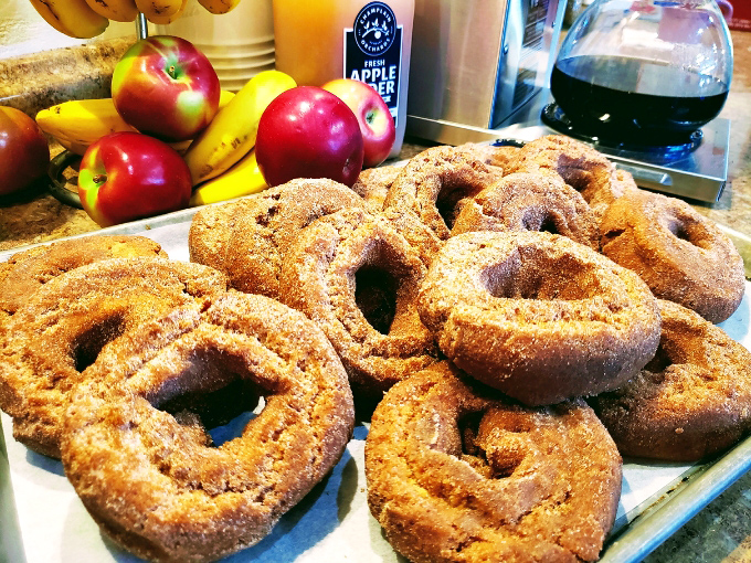 Apple cider donuts dusted with cinnamon sugar, posing with their apple ancestors &ndash; the circle of delicious life in one perfect Vermont scene.