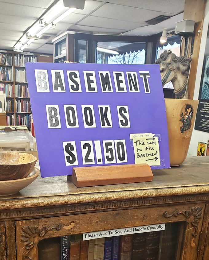 A cheerful purple sign announces basement bargains at $2.50, directing budget-conscious bibliophiles to hidden treasures waiting below.