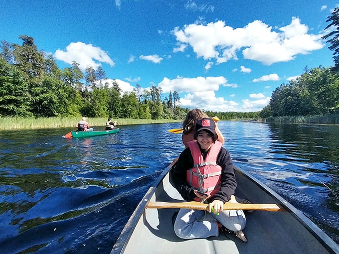 Paddlers glide through crystal waters, their canoes creating gentle ripples in this pristine northern paradise.