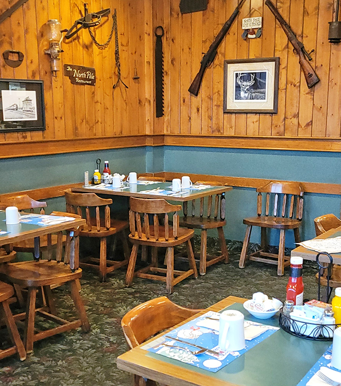 Rustic wooden chairs and blue accents create dining nooks where hunting memorabilia watches over your meal like woodland guardians.