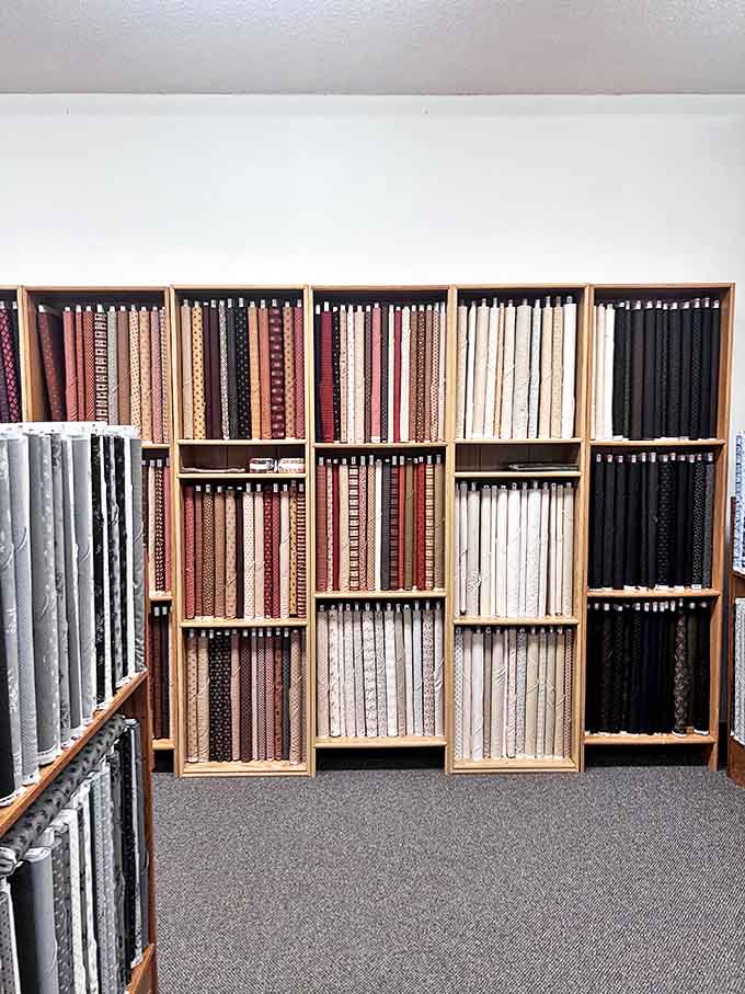 Fabric rolls organized with military precision &ndash; neutrals, patterns, and solids creating a textile library of possibilities.