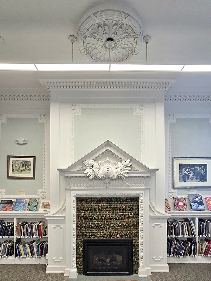 An elegant fireplace with ornate detailing creates a focal point that would make any book lover want to curl up with a classic.