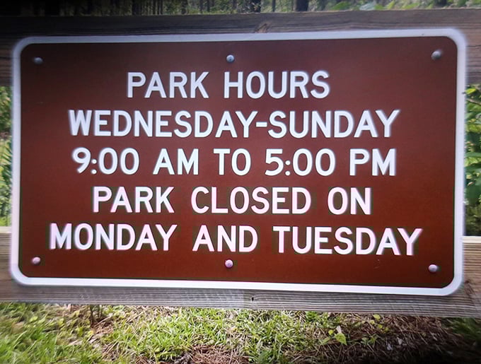 The park hours sign stands as a gentle reminder that even nature needs a weekend, closing Mondays and Tuesdays for a well-deserved rest.